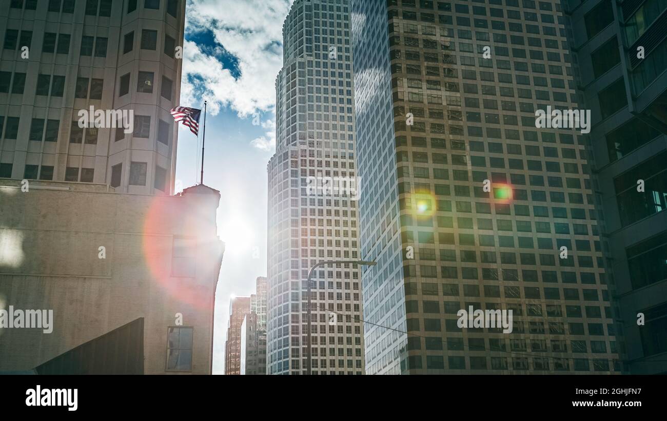 American flag on a pole between skyscrapers in backlight with lens ...