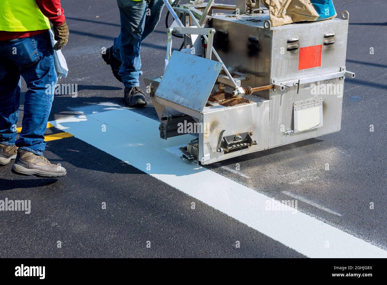 Workers paint new road surface stripes on new asphalt Stock Photo - Alamy