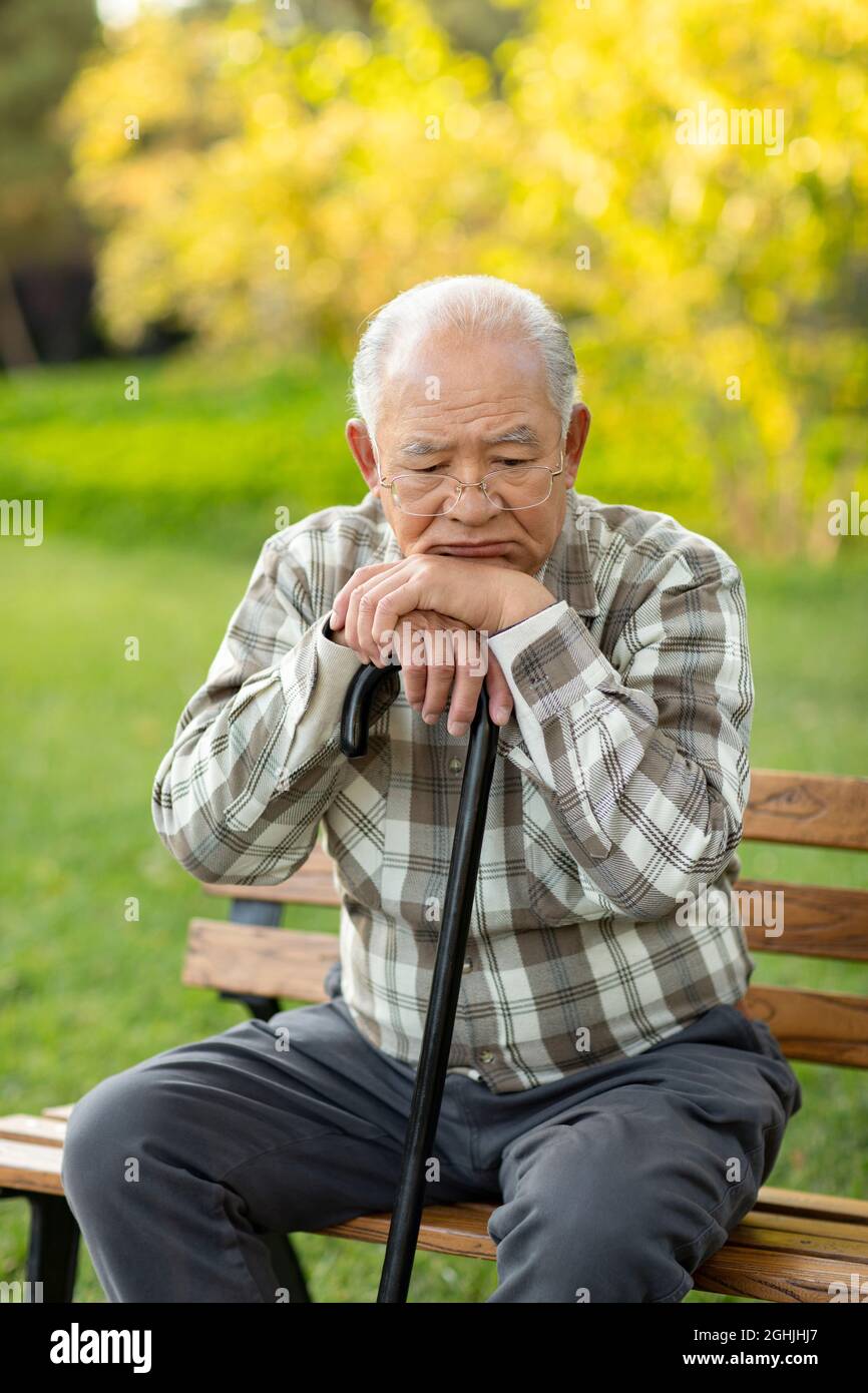 Lonely senior man sitting on park bench Stock Photo - Alamy