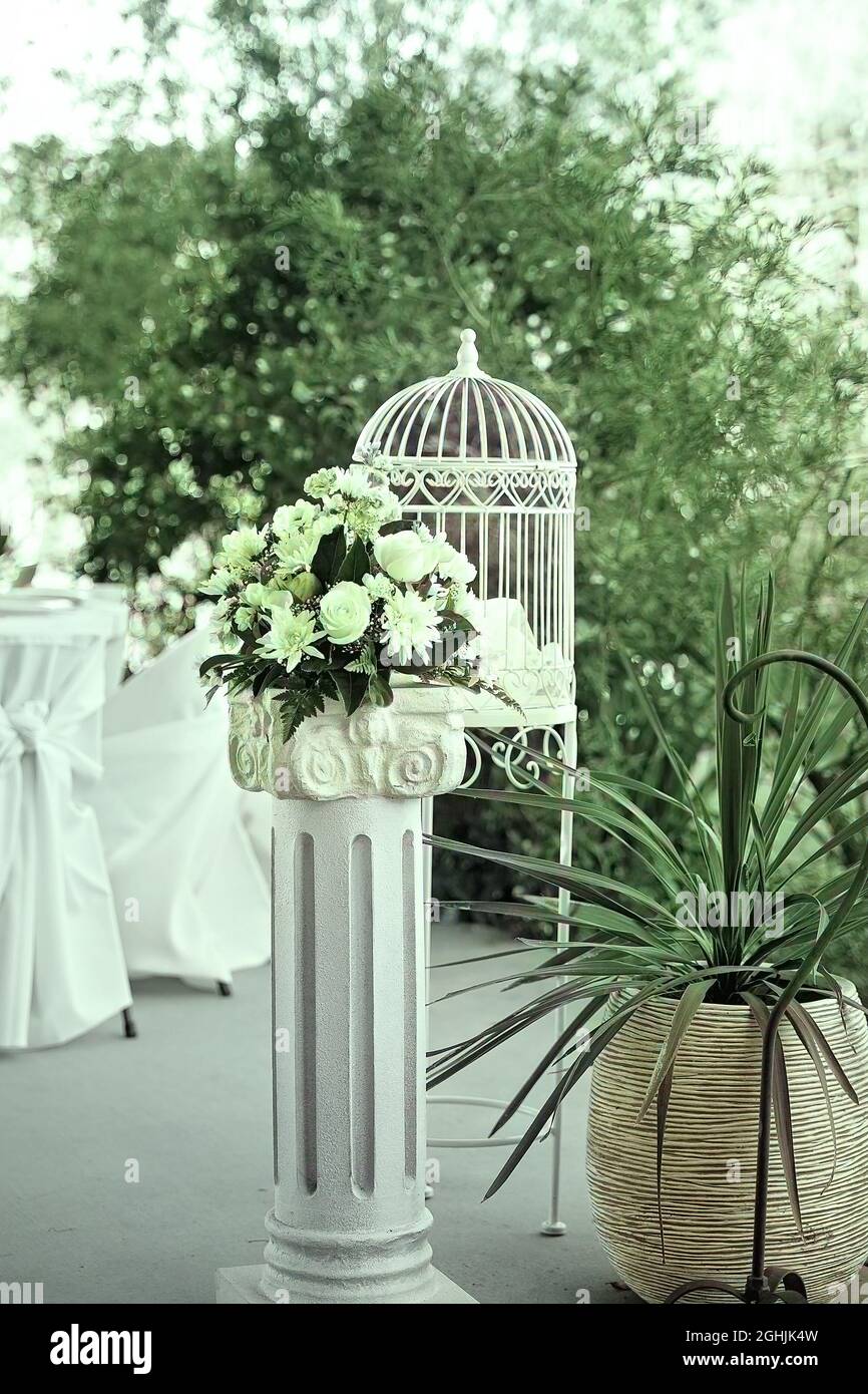 Elegant pedestal with floral bouquet, bird cage and pot plant in a ...