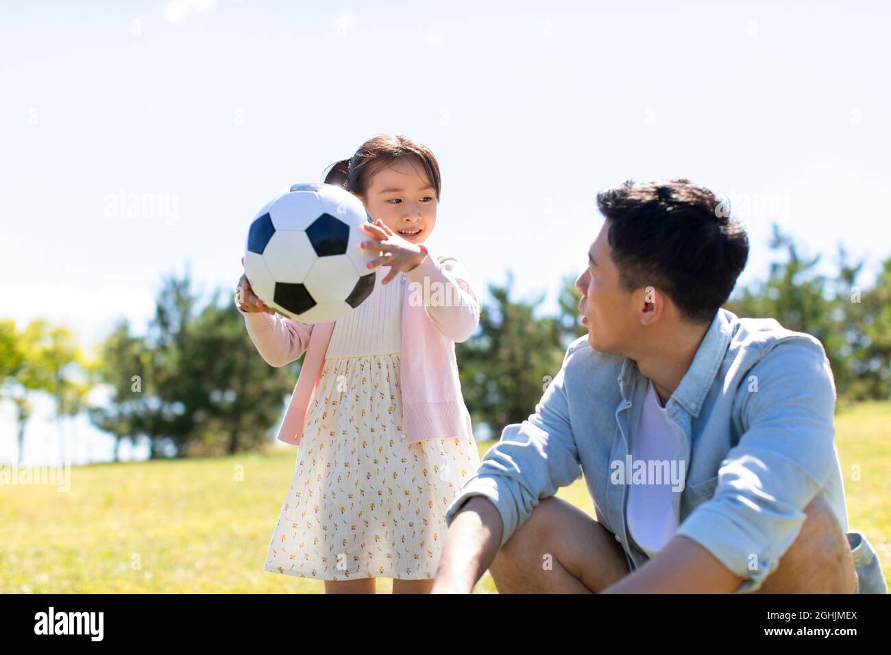 Happy father and daughter playing football in park Stock Photo - Alamy