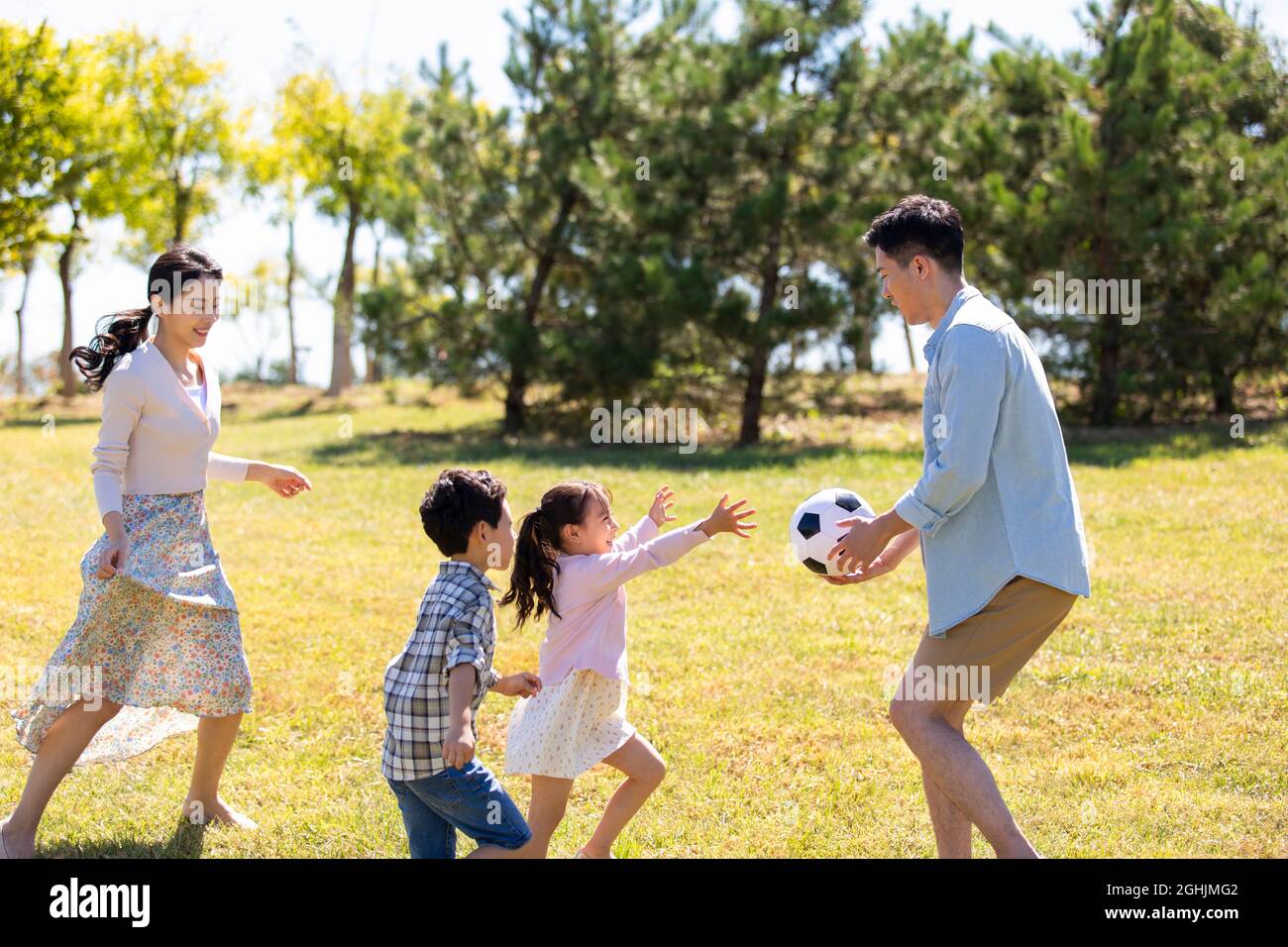 Happy family playing football in park Stock Photo - Alamy