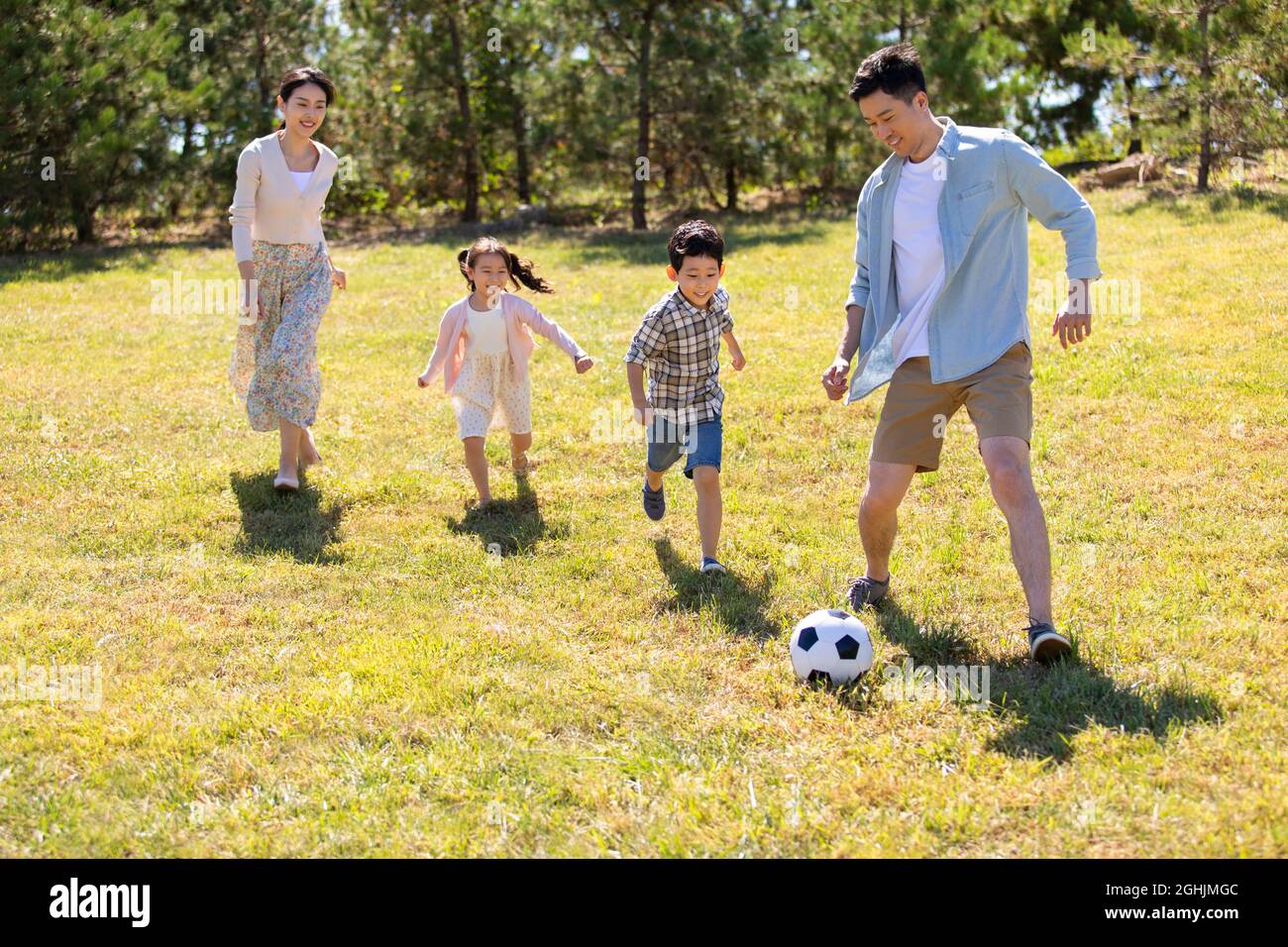 Happy family playing football in park Stock Photo - Alamy