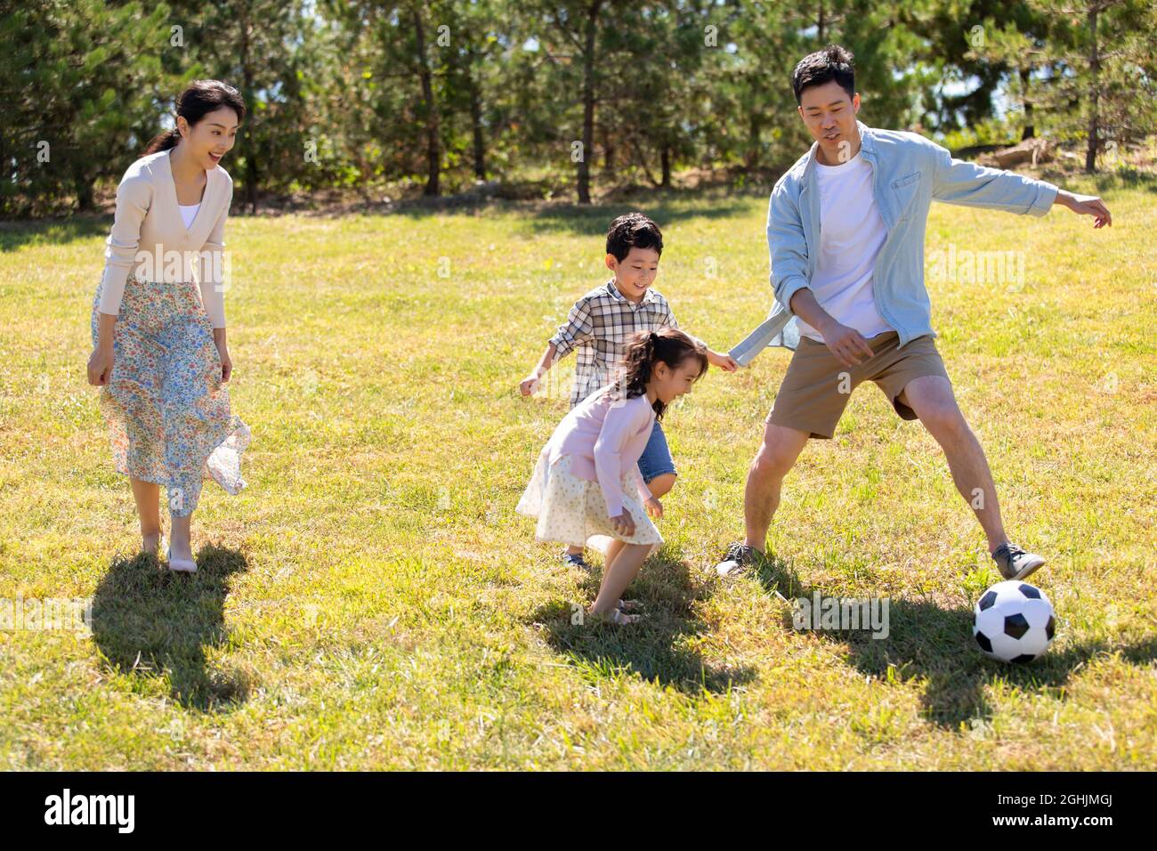 Happy family playing football in park Stock Photo - Alamy