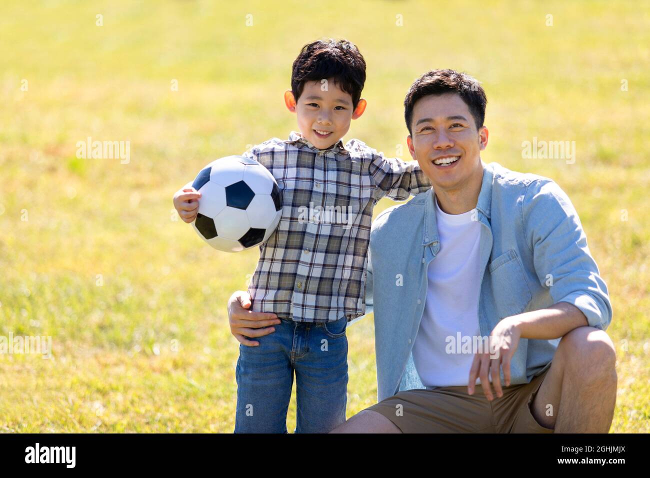 Happy father and son playing football in park Stock Photo - Alamy