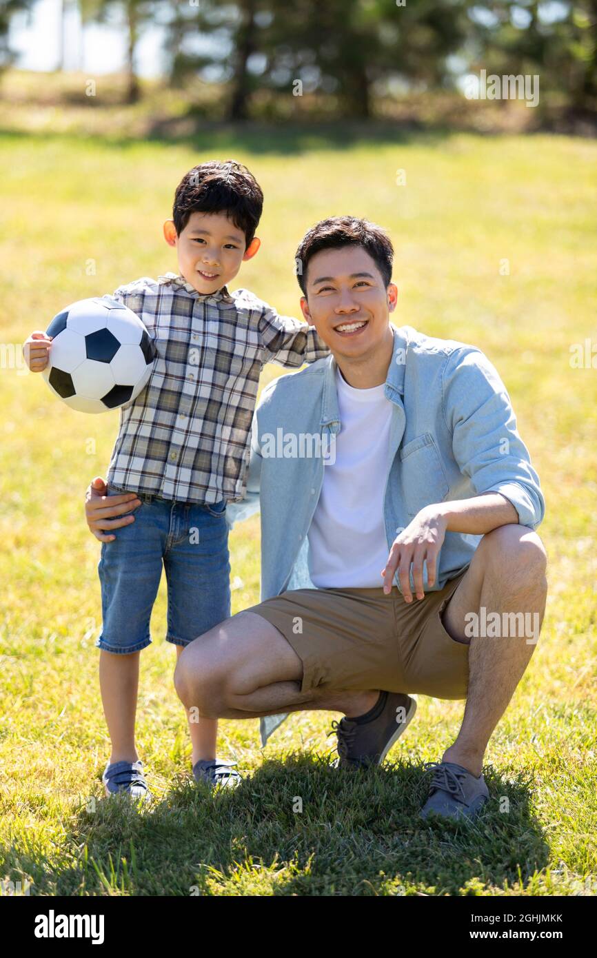 Happy father and son playing football in park Stock Photo - Alamy