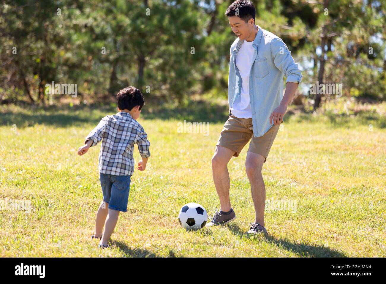Happy father and son playing football in park Stock Photo - Alamy