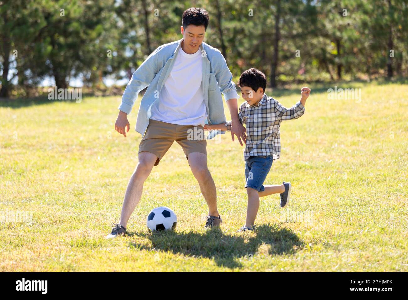 Happy father and son playing football in park Stock Photo - Alamy