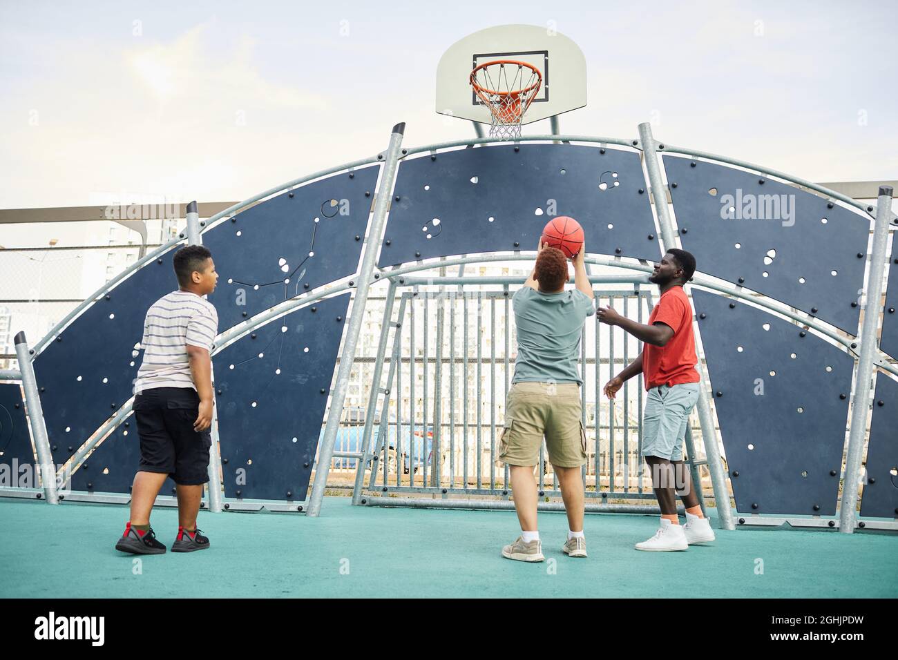 Boy throwing ball into basketball hoop under fathers control while ...