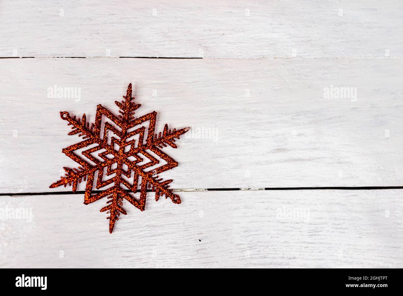Top view of a red snowflake decoration on a white table with copyspace ...