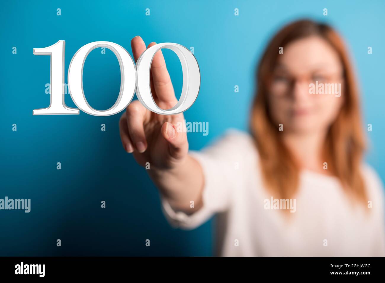 Closeup of a woman touching a 3d rendering of 100 on a blue background ...