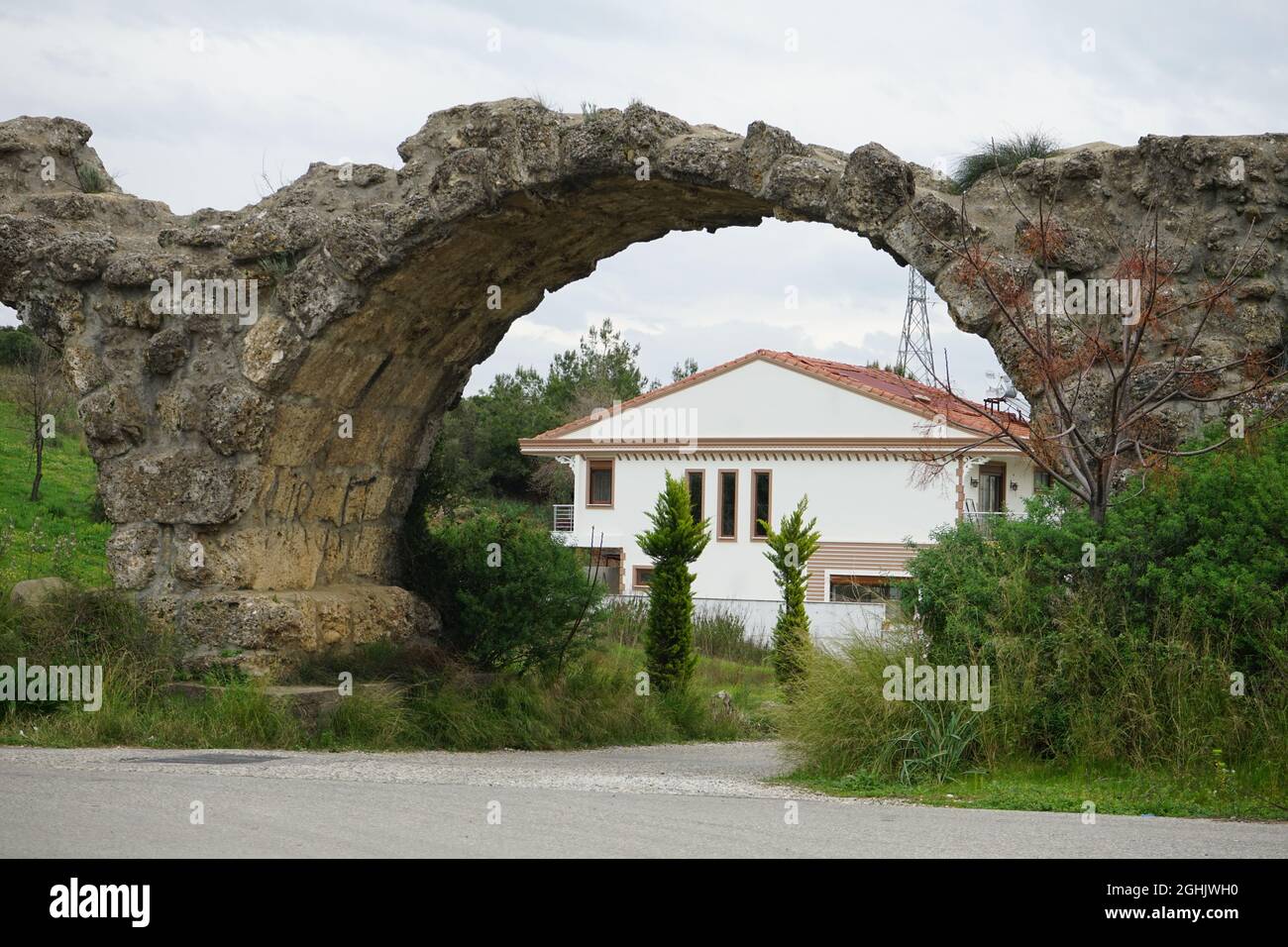 Close-up shot of a white house with a brick roof seen through a stone ...