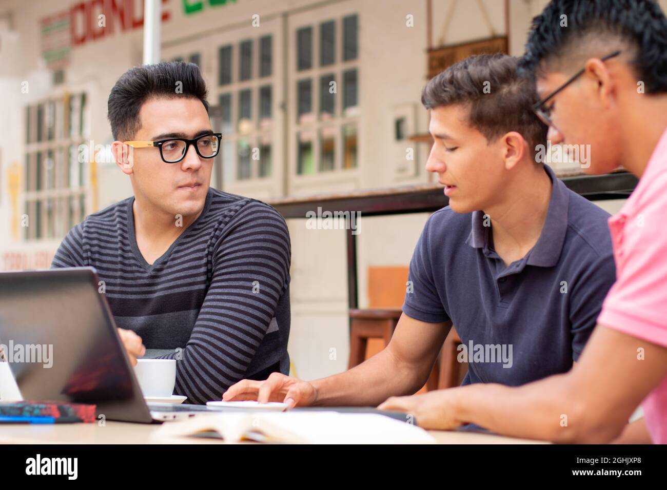 Three young people talking outdoors while using a laptop Stock Photo ...