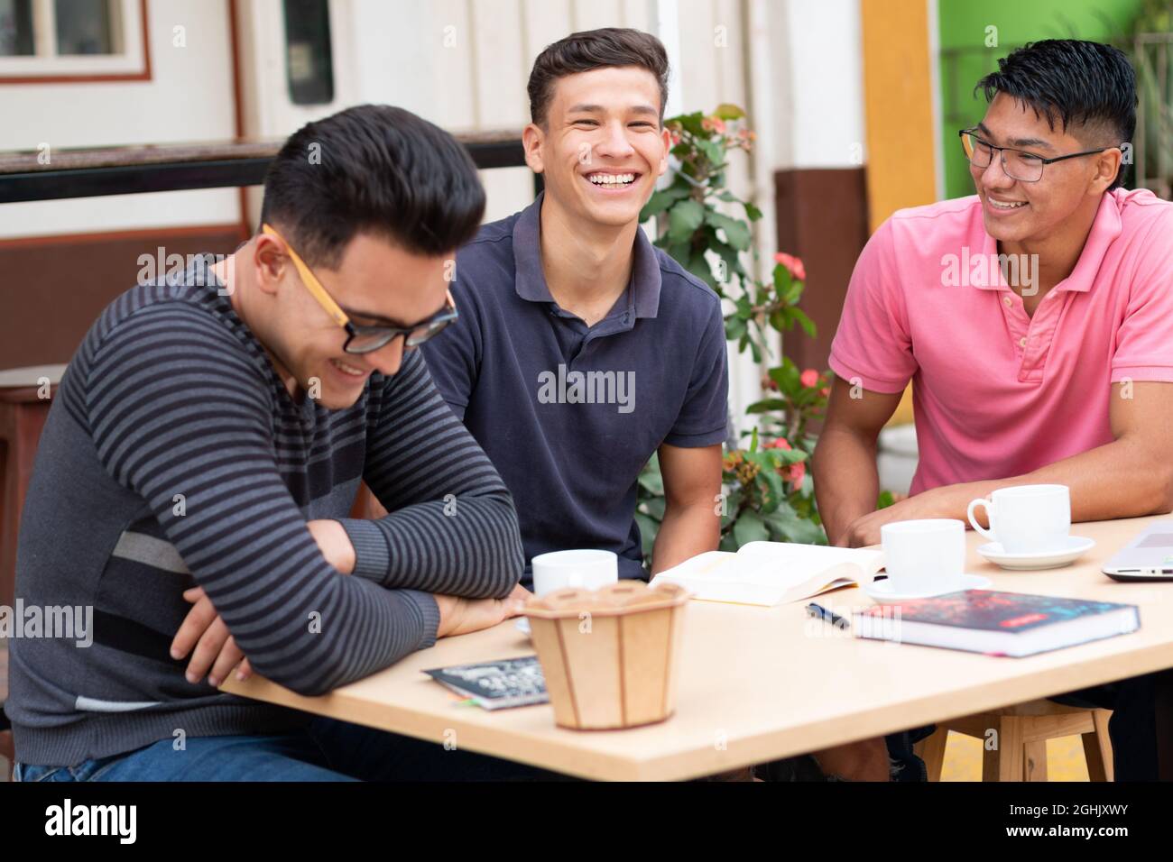 Three men sitting at a desk laughing in the open air Stock Photo - Alamy