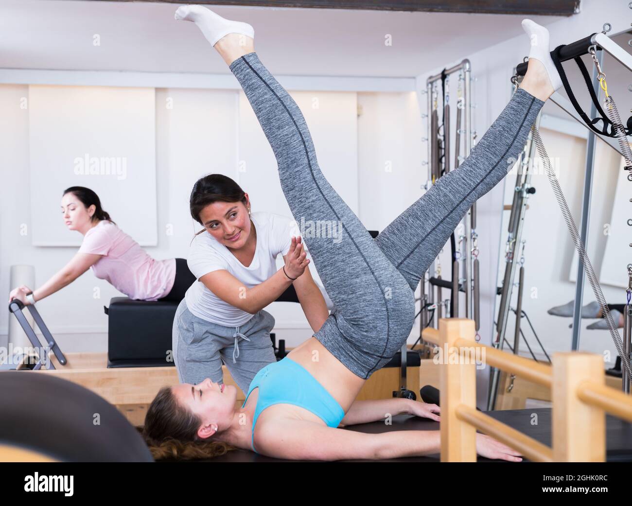Trainer controlling movements of woman doing pilates on reformer Stock ...