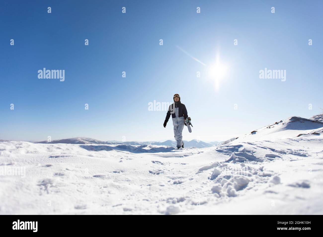 Young man walking with snowboard on the snow Stock Photo - Alamy
