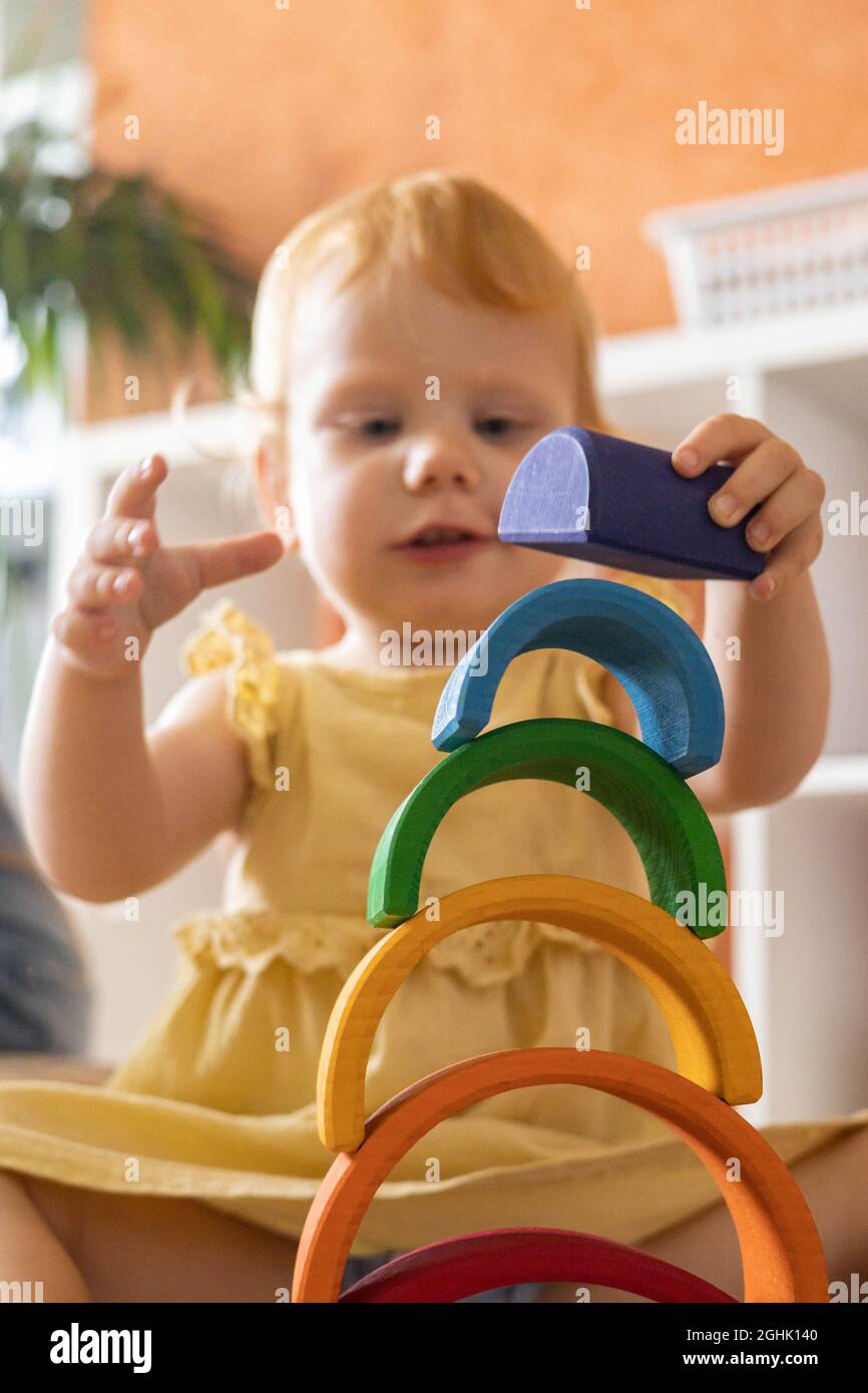 Baby girl in dress stacking rainbow arch block construction building ...