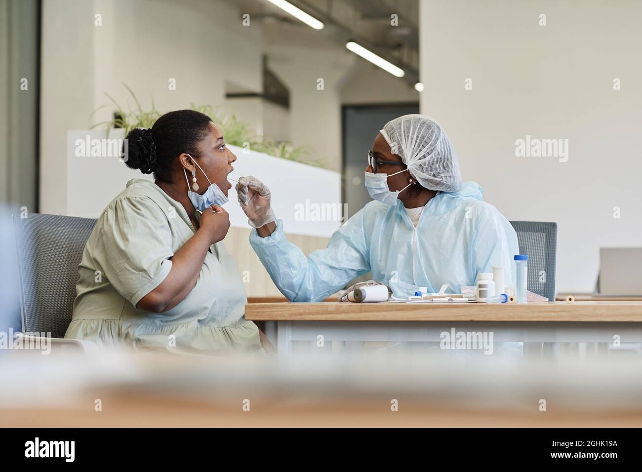 Medical professional doing Covid-19 test to woman with throat swab ...