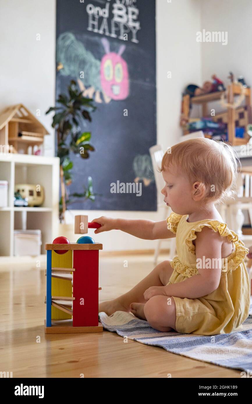 Happy girl toddler hitting wooden hammer on colored balls early ...
