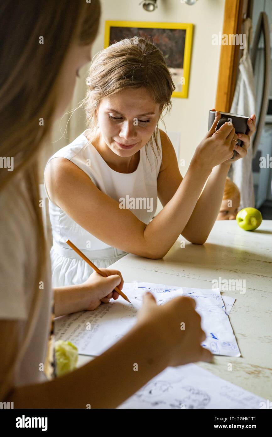 Teenager girl drawing picture on paper sheet or making notes use pen ...
