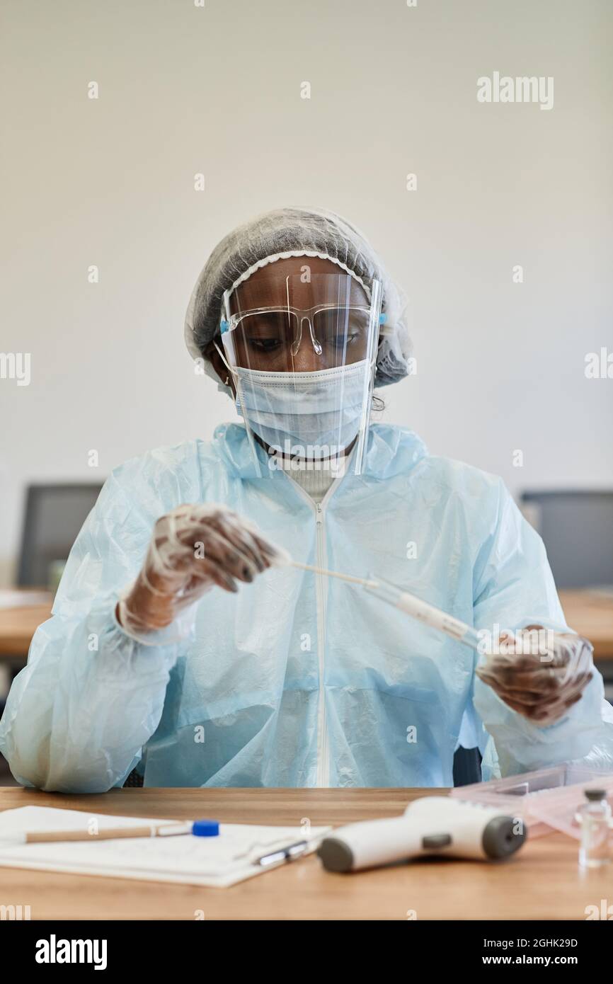 Serious medical nurse in PPE suit putting covid-19 test swab in test ...