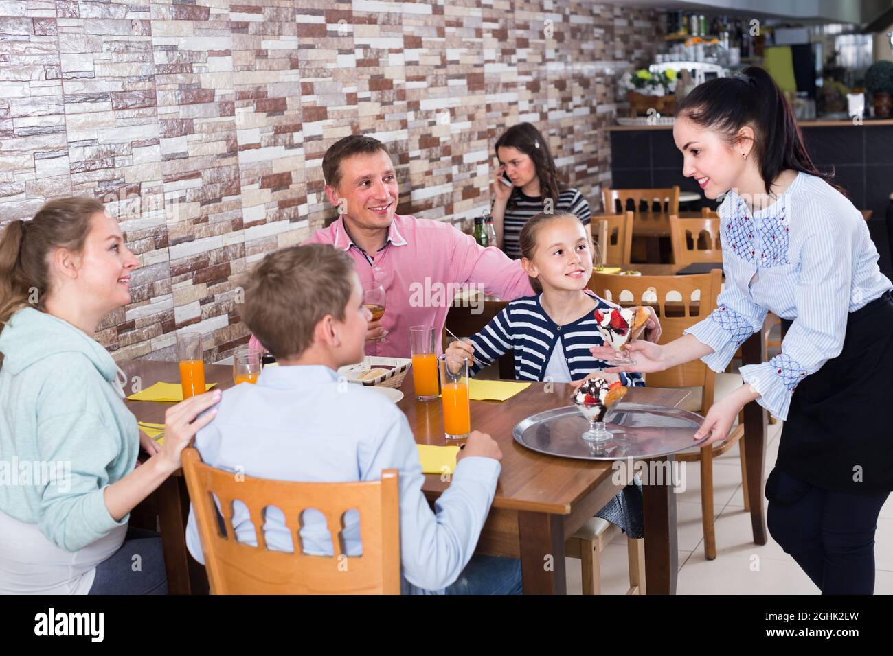 Young waitress is bringing delicious dessert to young visitors Stock ...