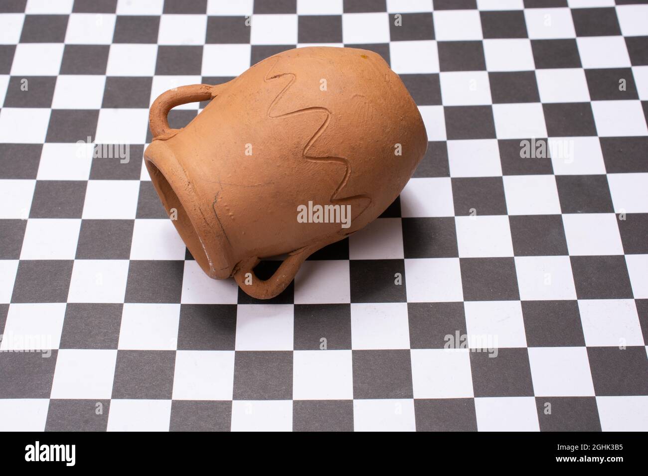 Closeup of a clay jug on a checkered surface Stock Photo - Alamy