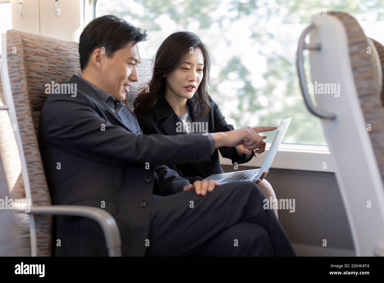 Successful business people using laptop on high-speed train Stock Photo ...