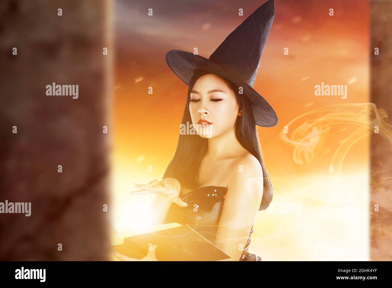 Asian witch woman with spellbook showing magic on her hand with ...