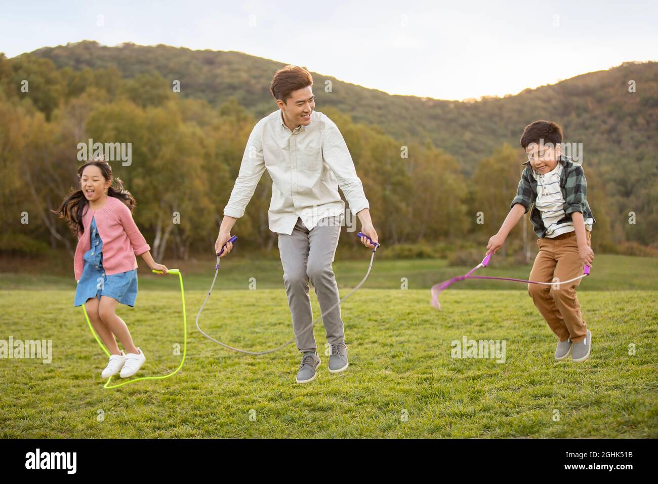 Happy young family jumping ropes outdoors Stock Photo - Alamy