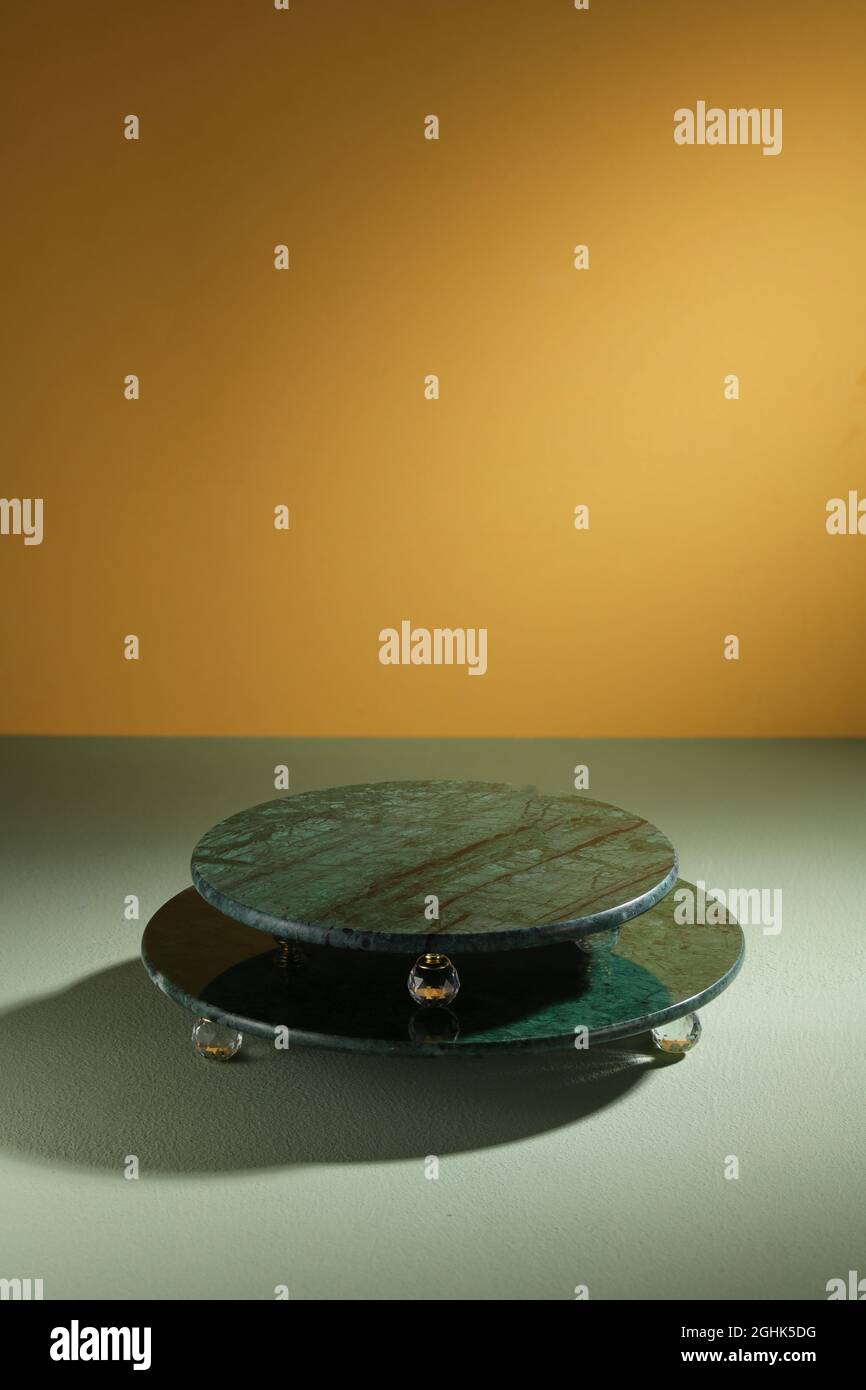 Set of two marble trays with overlapping legs on green table with light ...