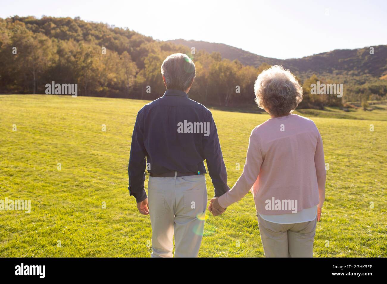 Happy senior couple holding hands walking Stock Photo - Alamy