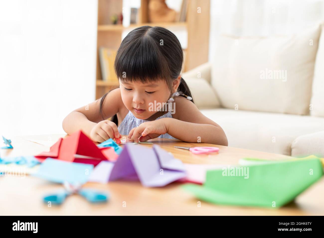 Cute girl doing paper craft in living room Stock Photo - Alamy