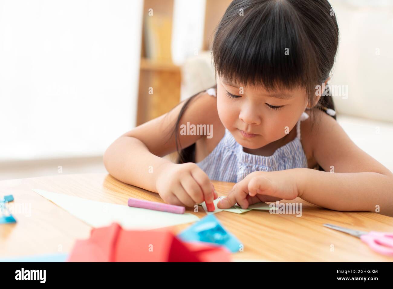 Cute girl doing paper craft in living room Stock Photo - Alamy