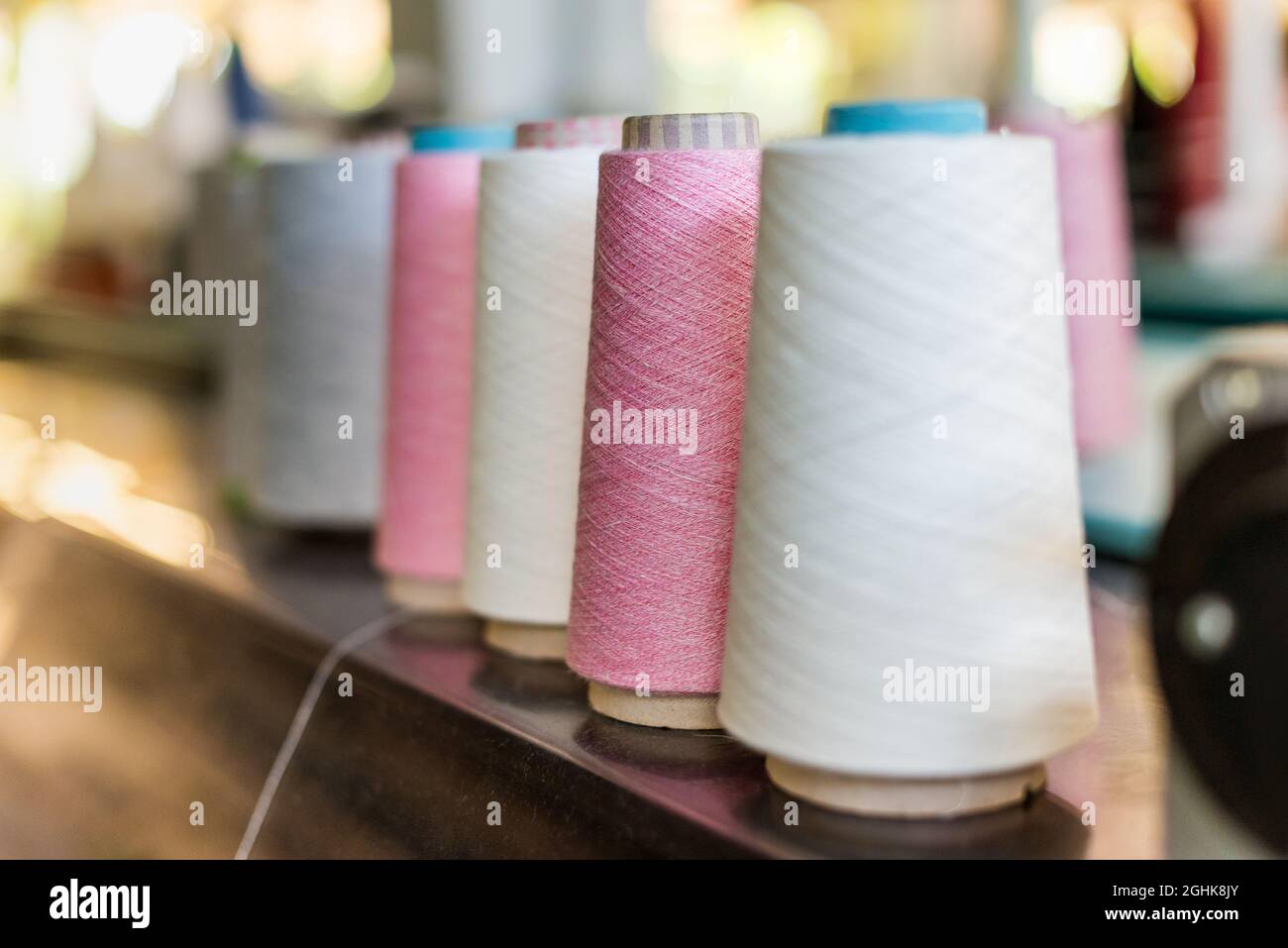 Receding line of alternating reels of pink and white cashmere yarn in a ...