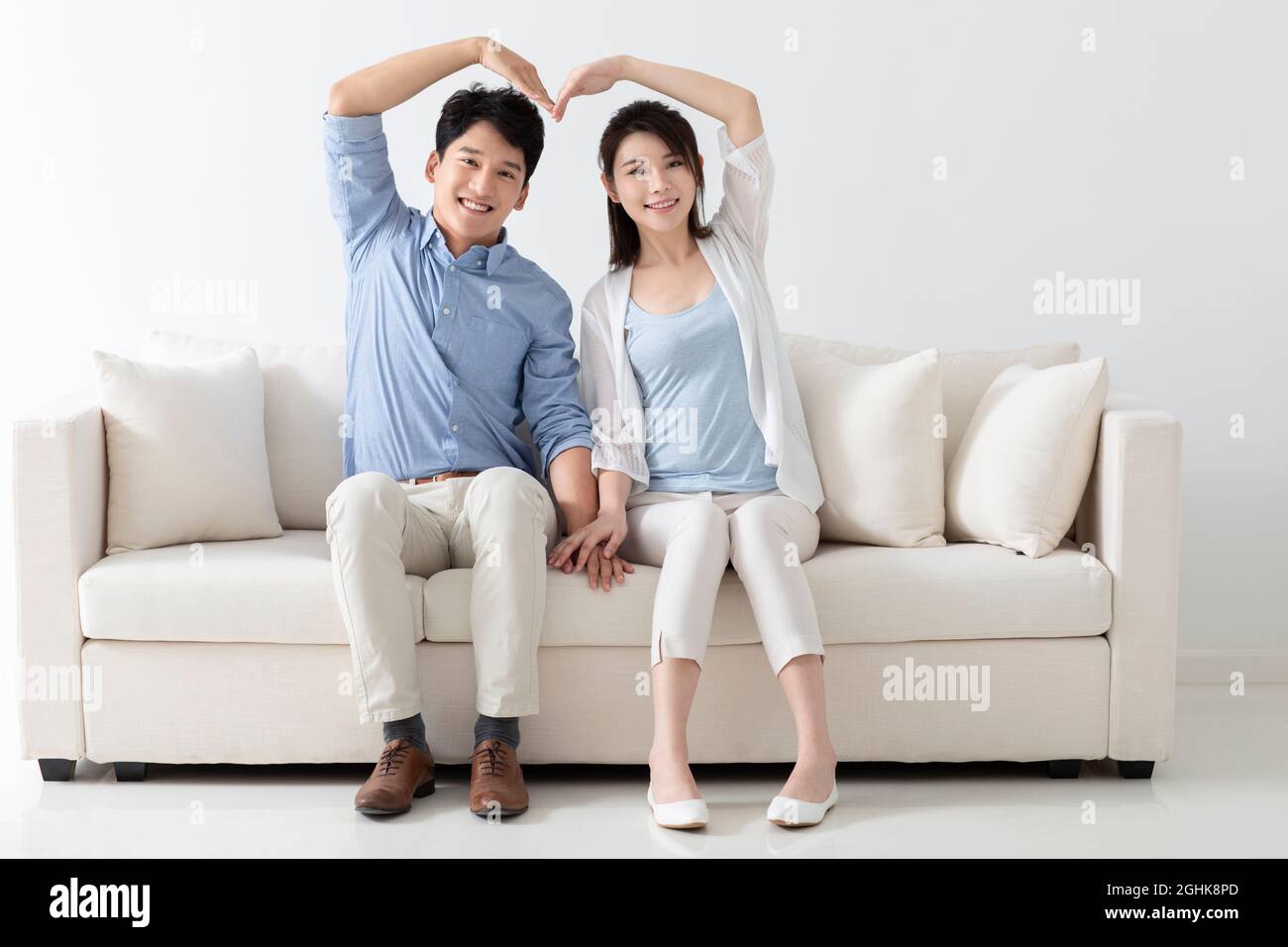 Cheerful young couple making heart shape with their hands Stock Photo ...