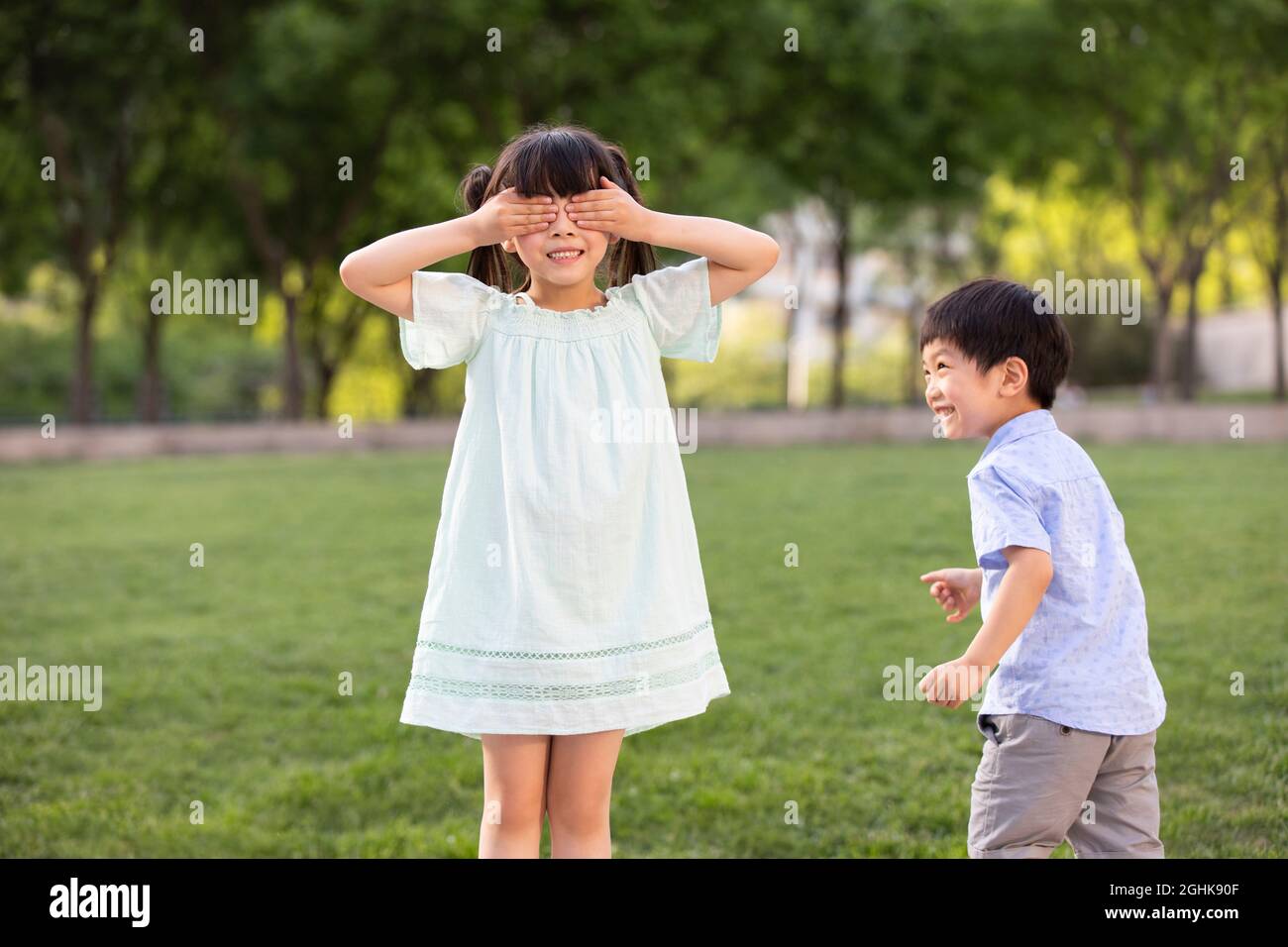 Two children playing hide and seek in park Stock Photo - Alamy