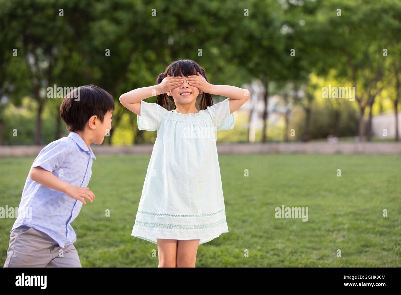 Two children playing hide and seek in park Stock Photo - Alamy