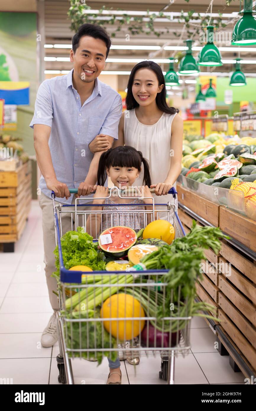 Happy young family shopping in supermarket Stock Photo - Alamy