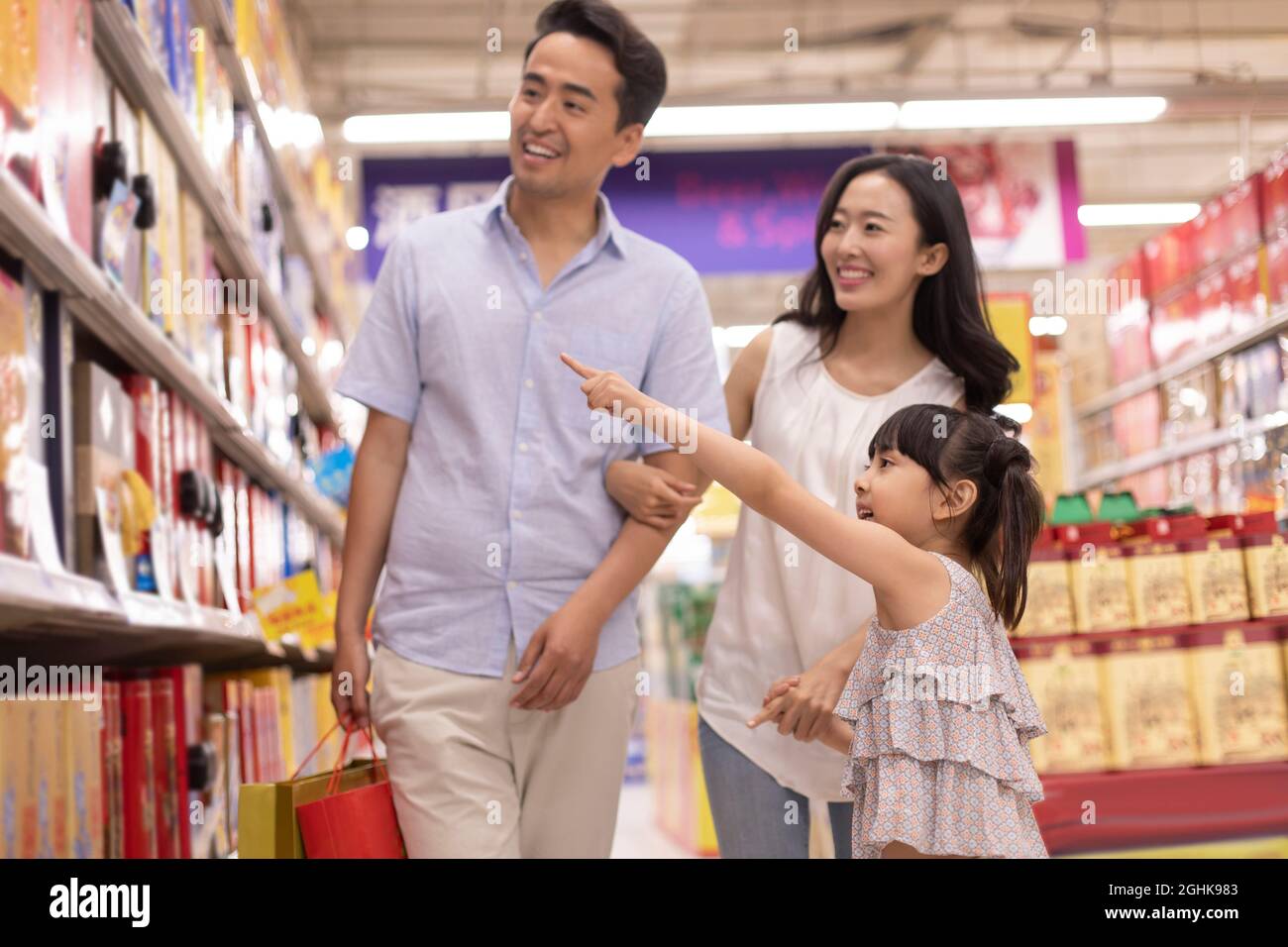 Happy young family shopping in supermarket Stock Photo - Alamy