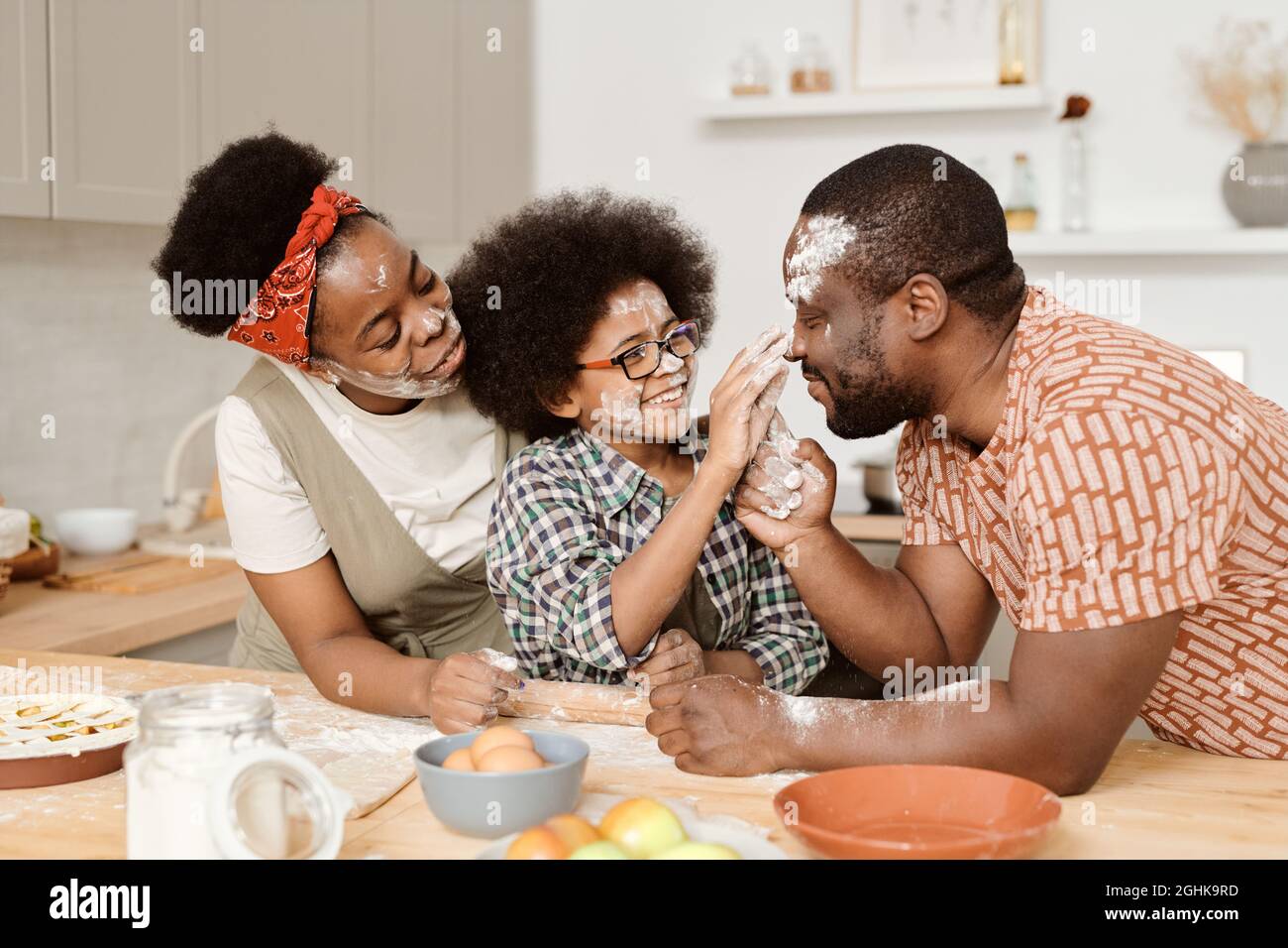Cute little boy with floured hands touching face of his father by ...