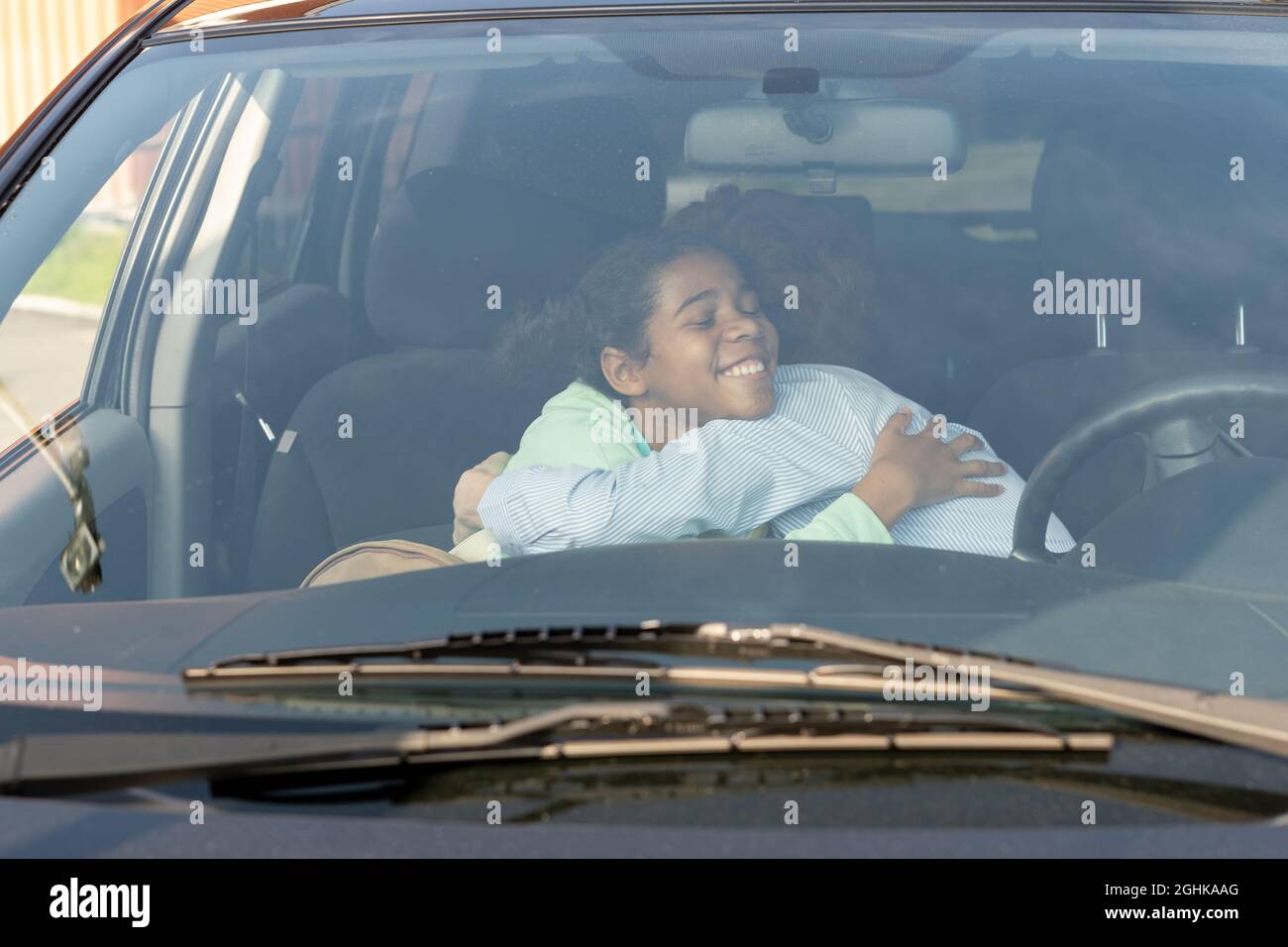 Affectionate mom and daughter giving each other goodbye hug in the car ...