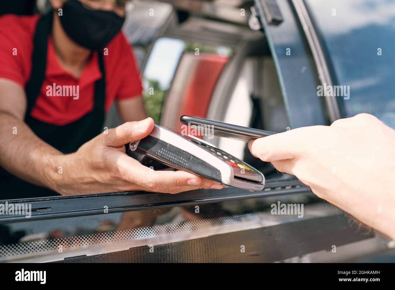 Seller of takeout food holding payment terminal in window of truck ...