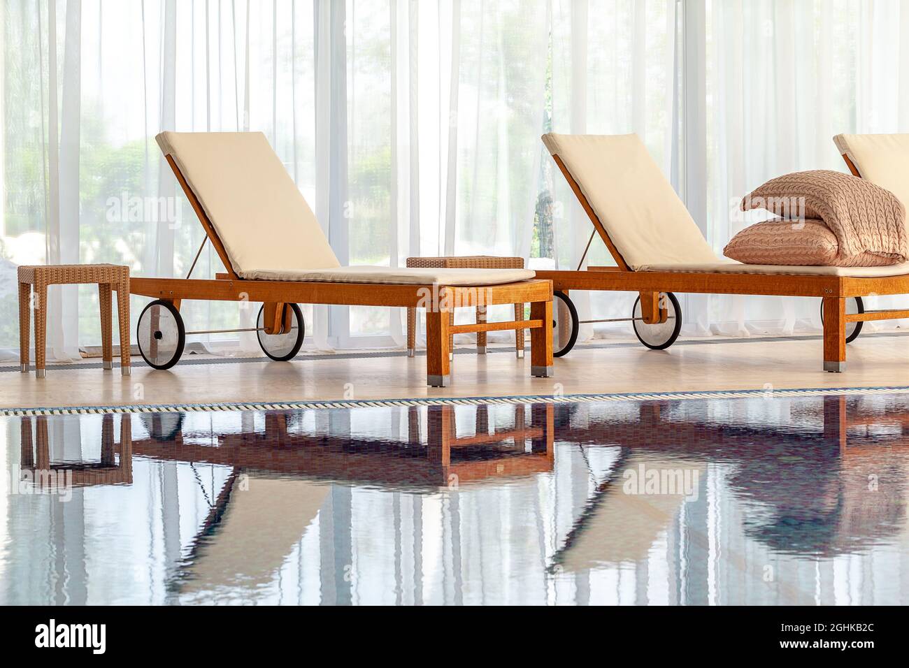 Wooden chaise lounges with mattresses against wide window in home ...