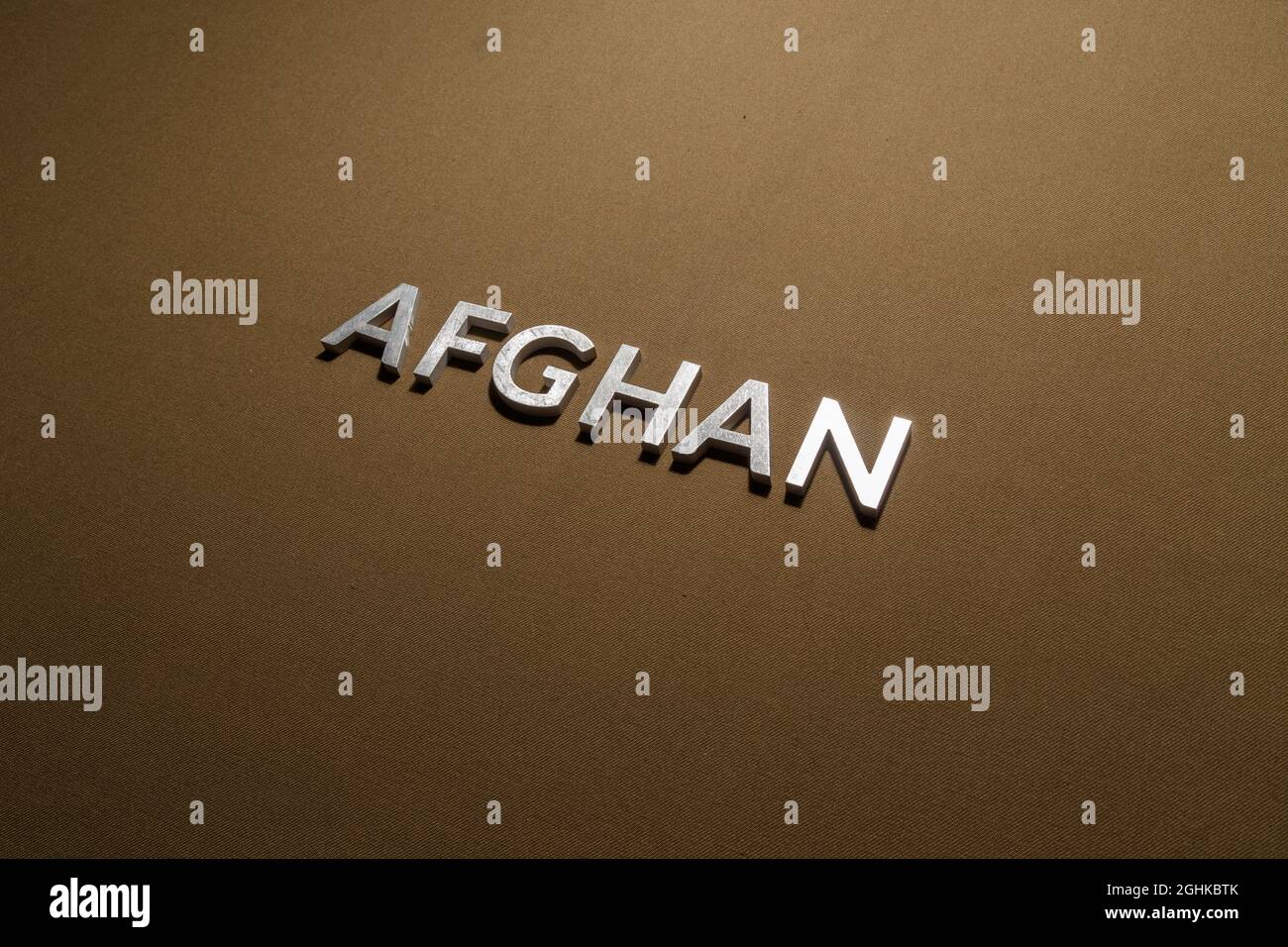 the word afghan laid with silver metal letters on rough tan khaki ...