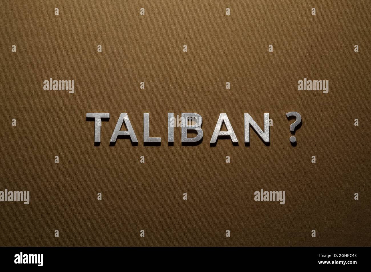 the question taliban laid with silver metal letters on rough flat tan ...