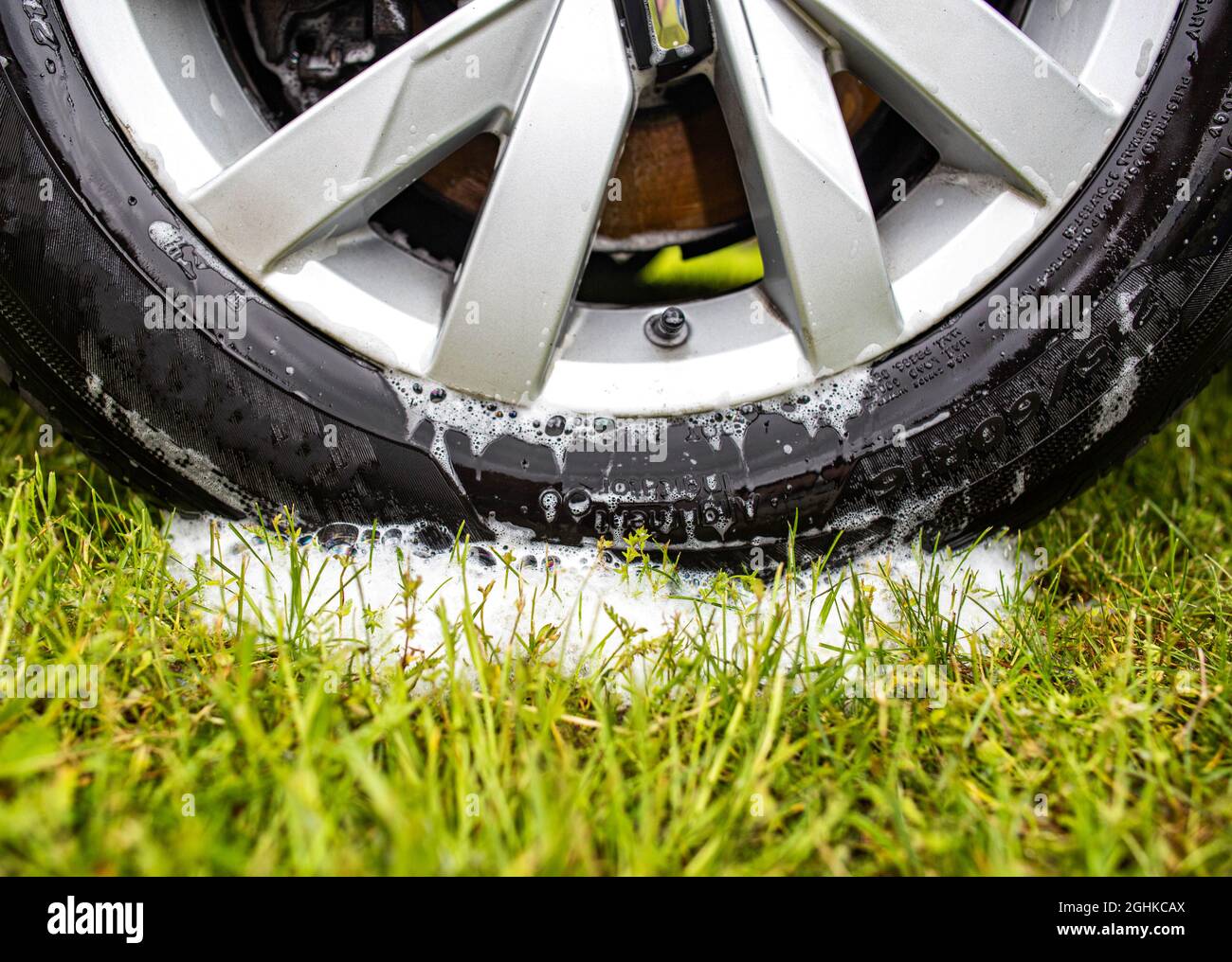 Clean car wheel rim after washing with car shampoo, foam on the grass ...