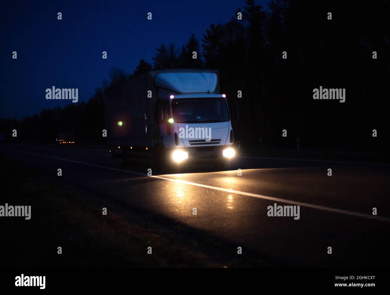 The van transports cargo with the headlights on at night, in the ...