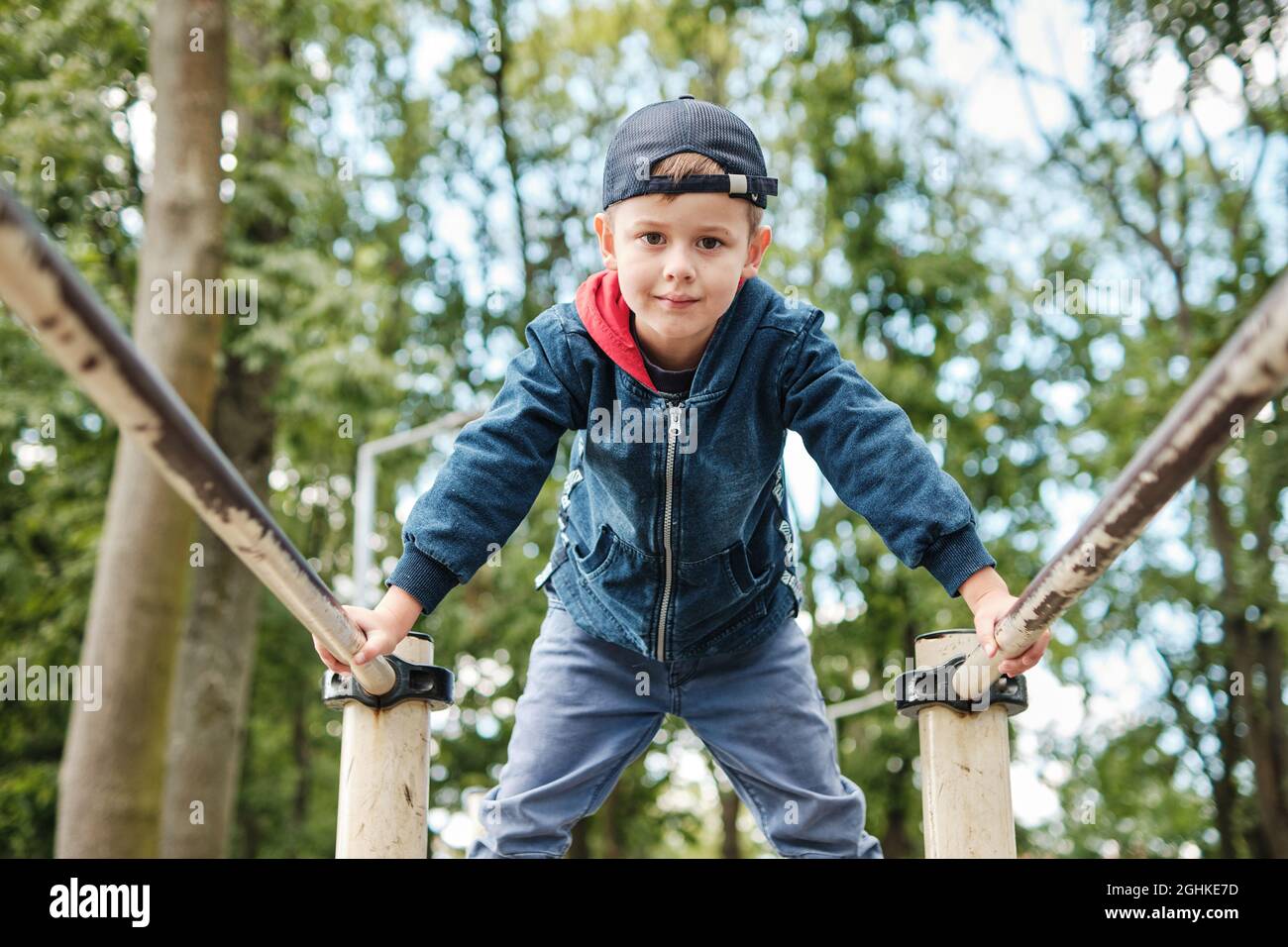 The child performs exercises on parallel bars on the street. Active ...