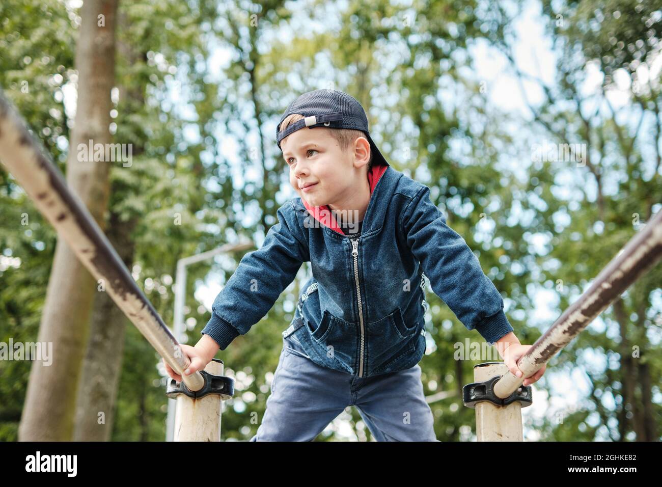 The child performs exercises on parallel bars on the street. Active ...
